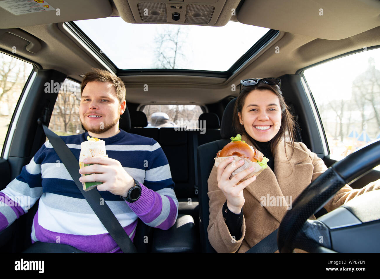 young couple eating fast food in car Stock Photo - Alamy