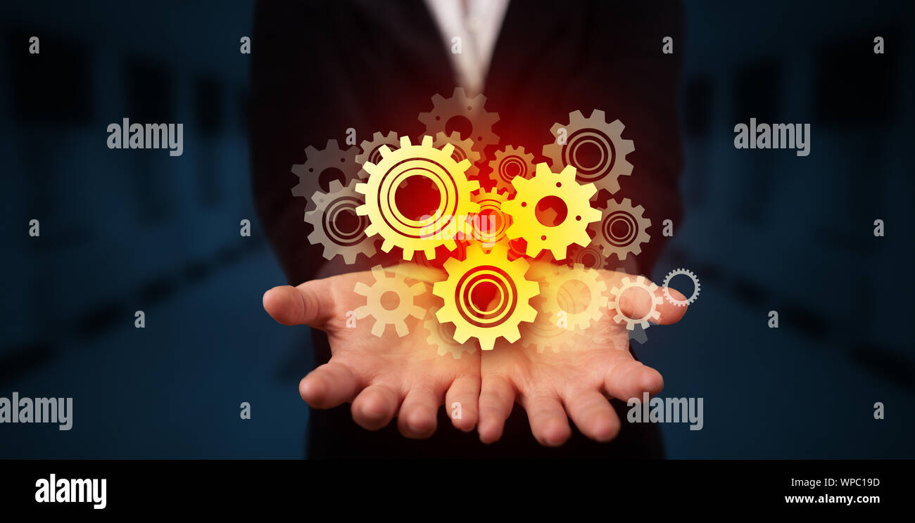 Hand holding gears in his hand Stock Photo - Alamy