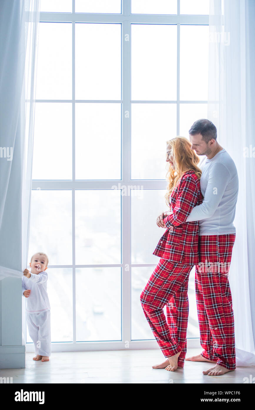 Happy family standing near a huge modern plastic window. Mother, father ...