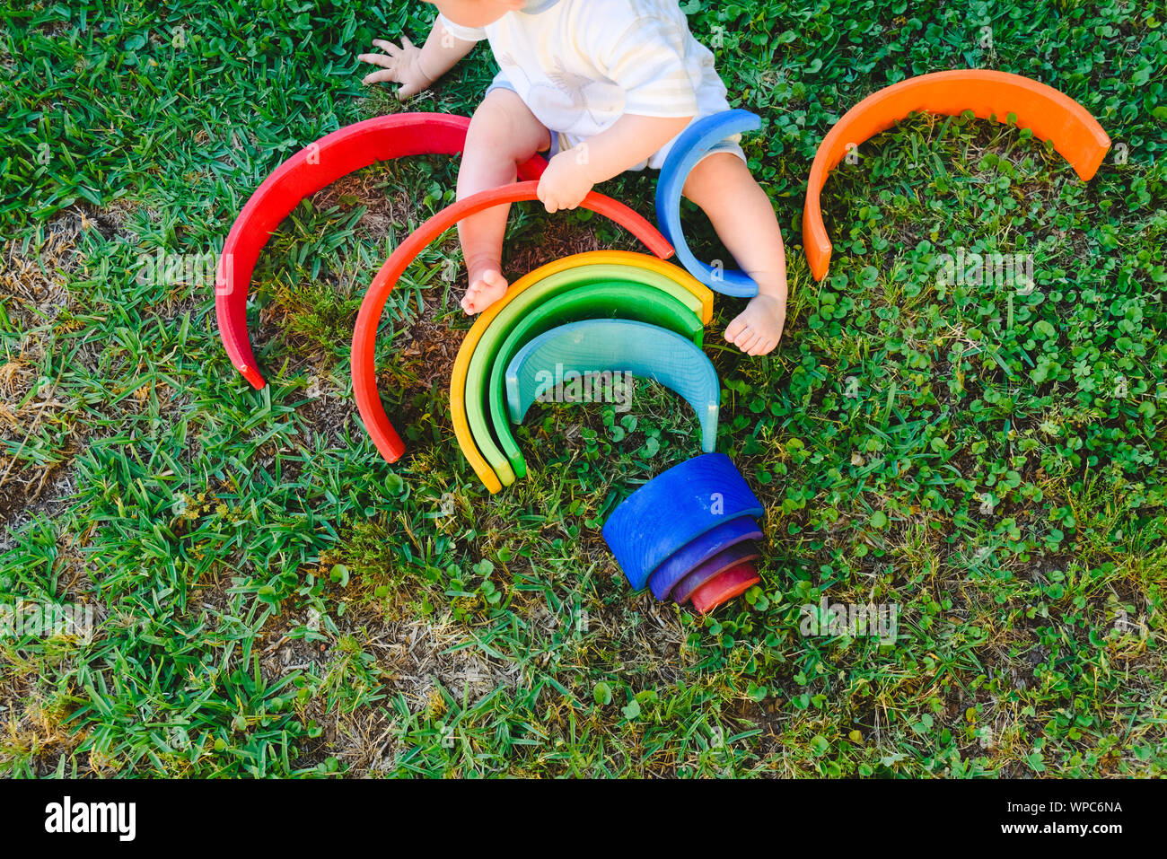 Baby playing with a colorful wooden rainbow on the grass, children's ...