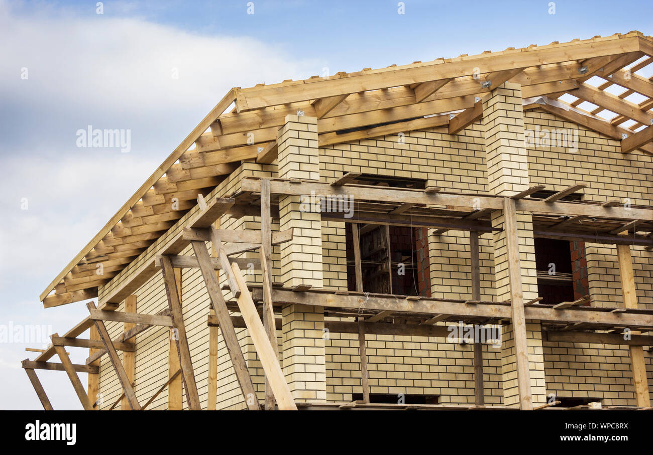 A large yellow brick house is being built, and the roof is made of wood ...