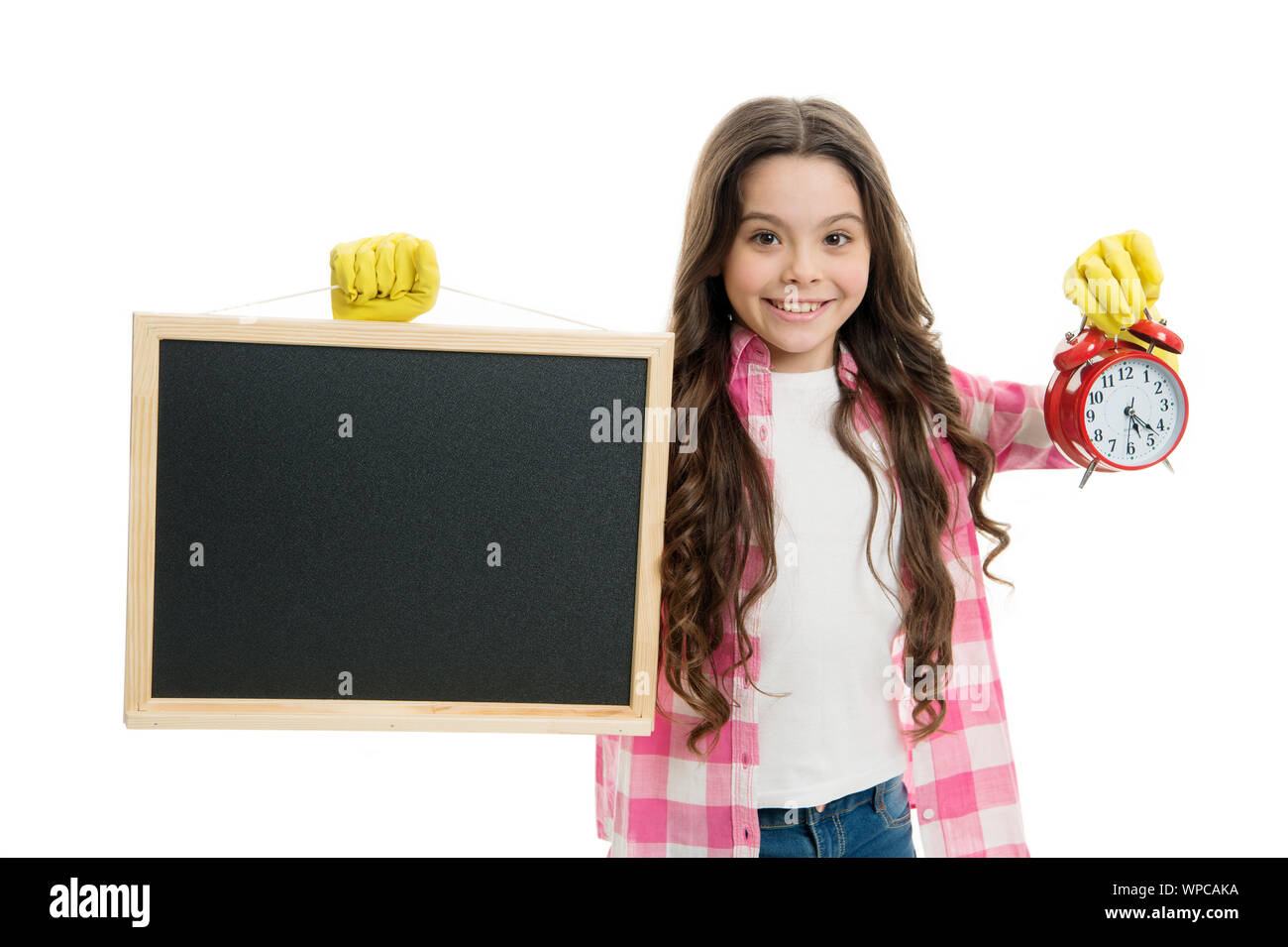 Its class time. Happy little girl holding blank blackboard and alarm ...
