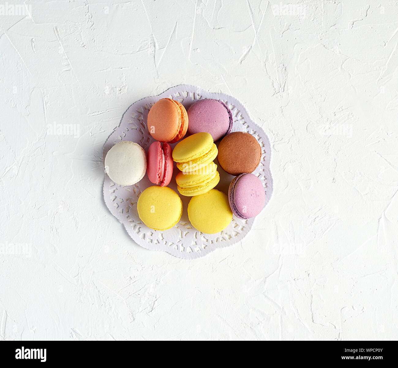 round multi-colored baked macarons with cream, white background, top ...