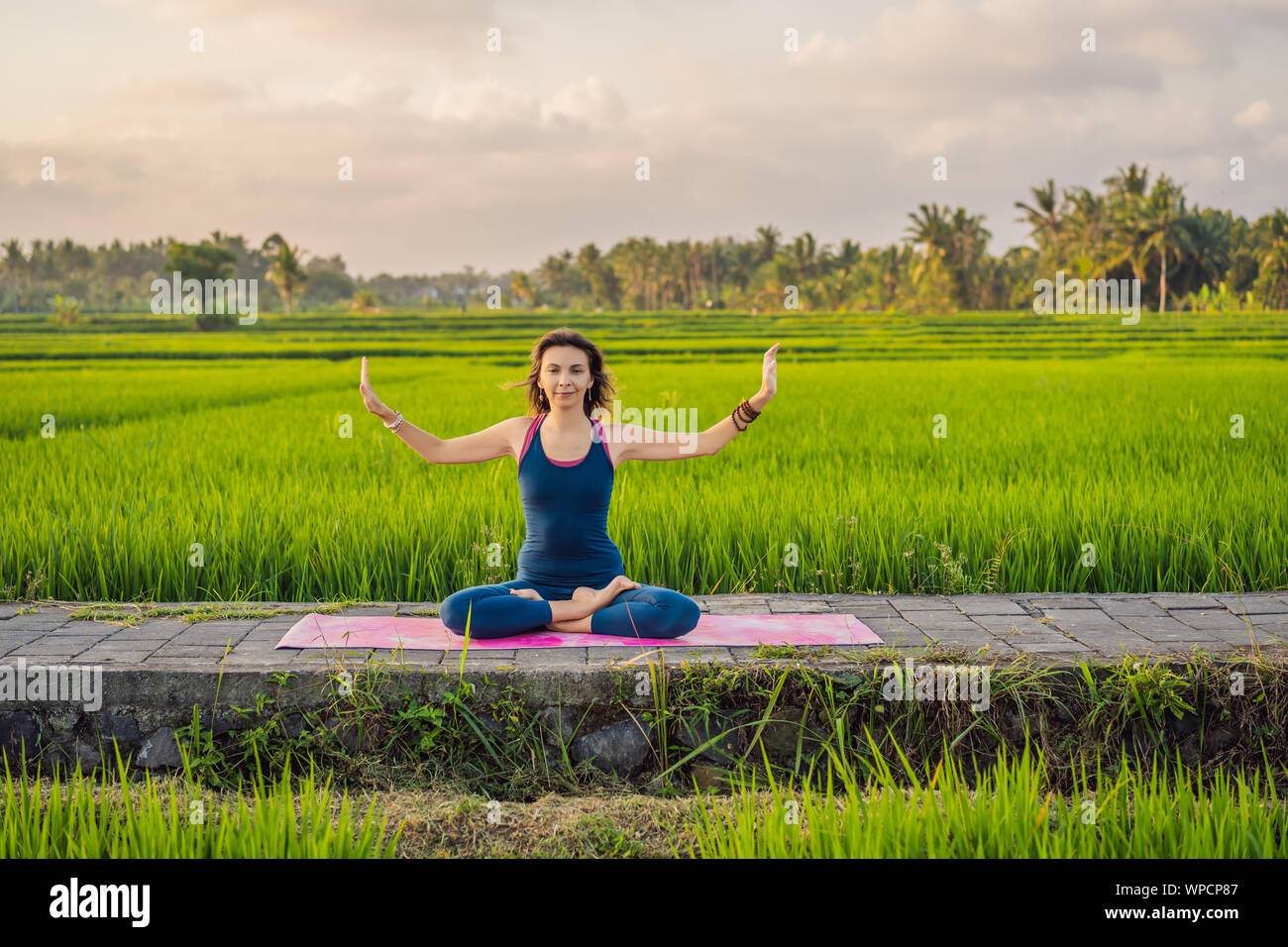 Young woman practice yoga outdoor in rice fields in the morning during ...