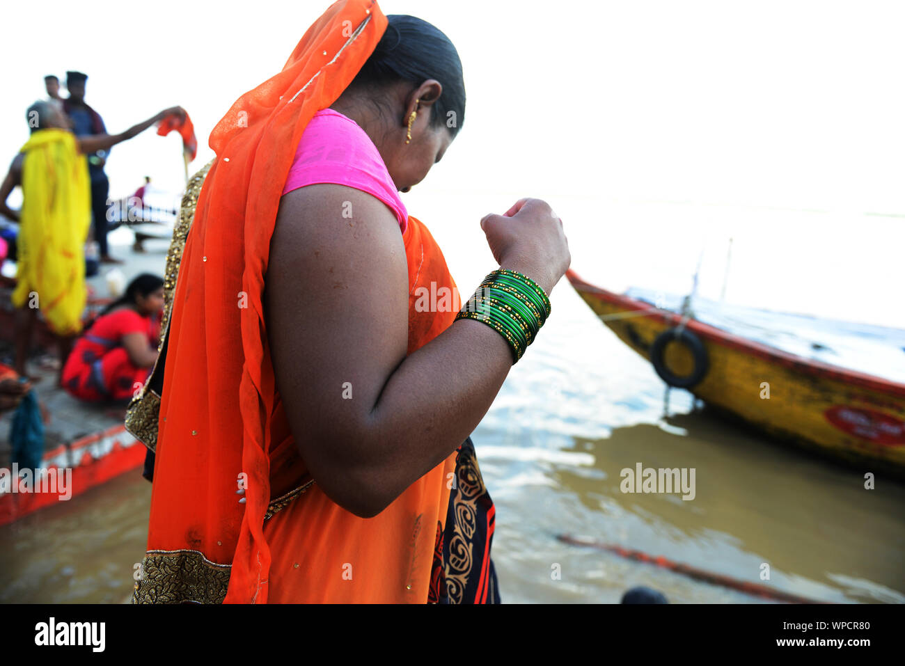An Indian woman praying by the Ganges river in Varanasi Stock Photo - Alamy
