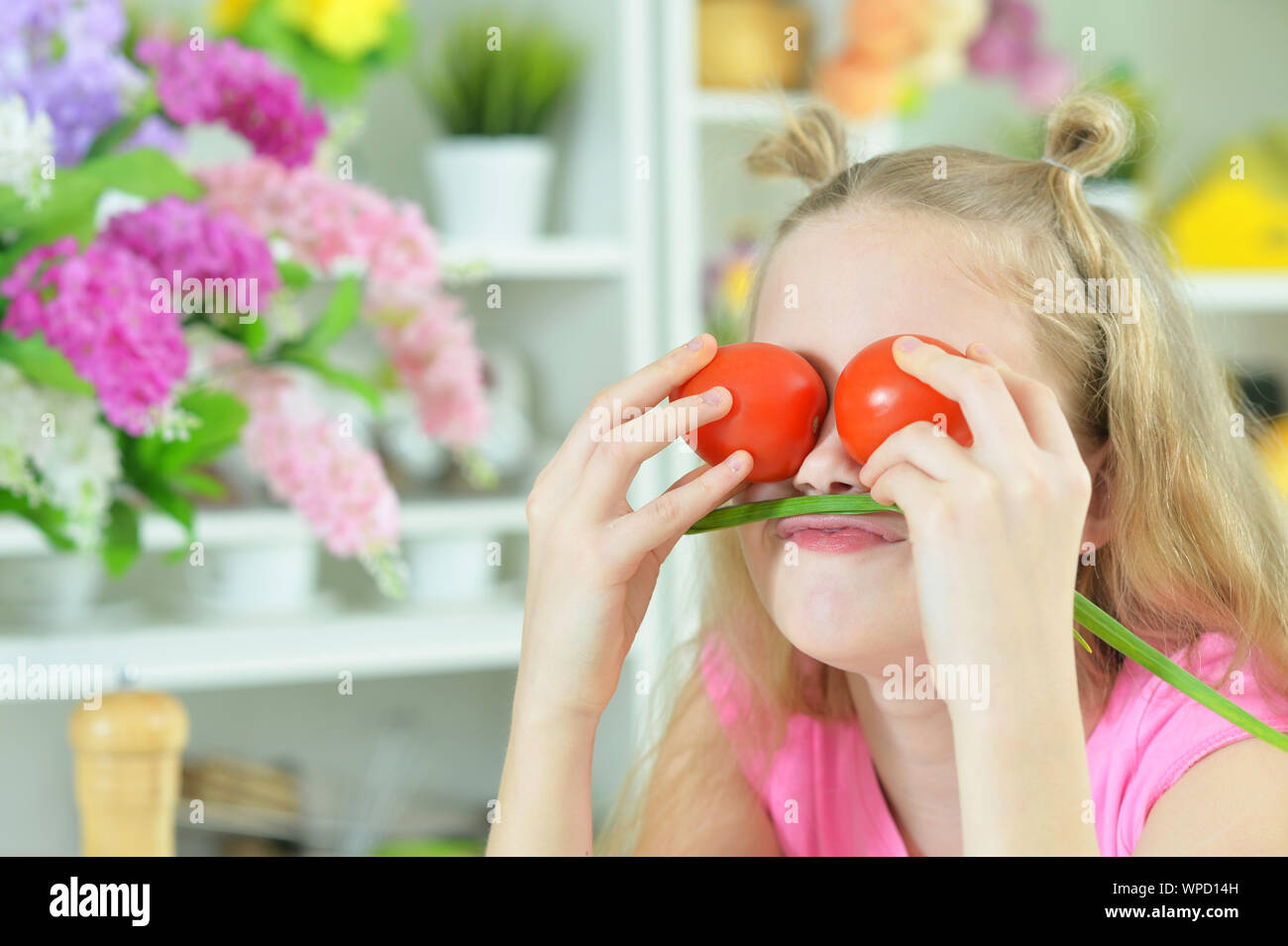 Cute girl playing with tomatoes in kitchen Stock Photo - Alamy