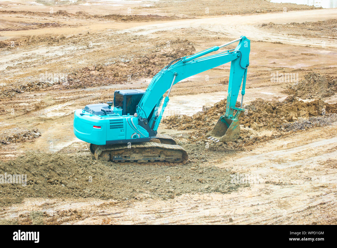Green mini Crawler excavator hydraulicis digging a hole concrete and ...