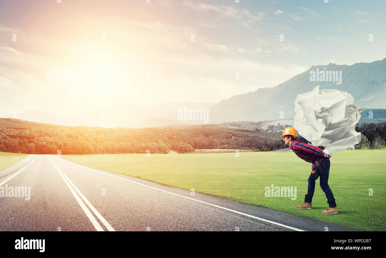Builder man carrying paper ball on his back Stock Photo - Alamy
