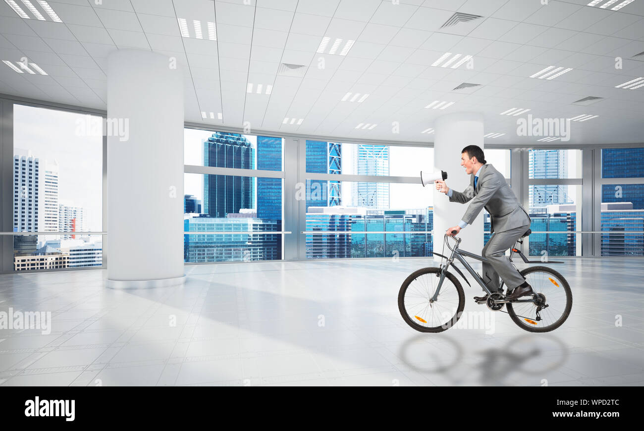 Manager in business suit riding bicycle at conference hall. Businessman ...