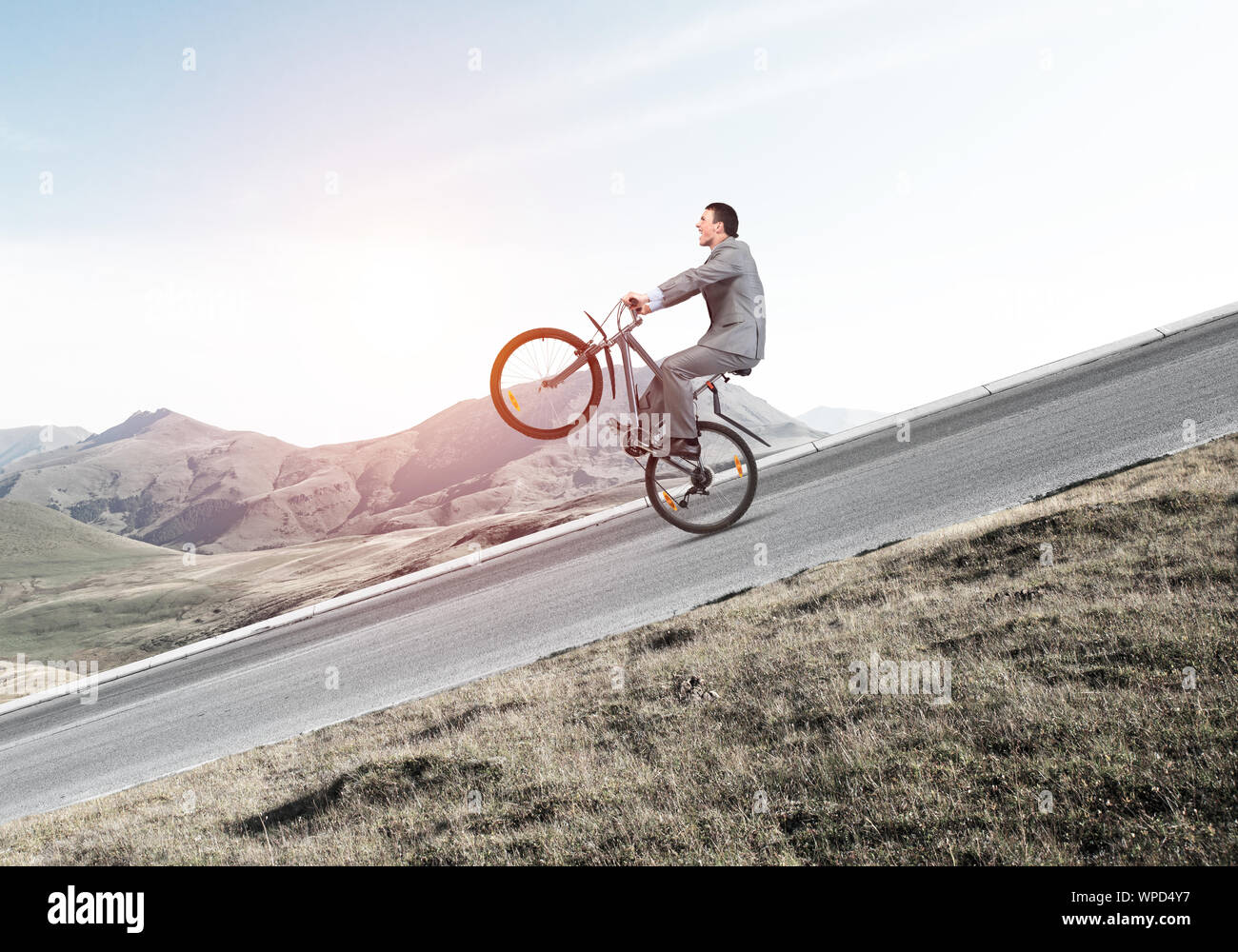 Businessman riding downhill by bike. Nature landscape with copy space ...