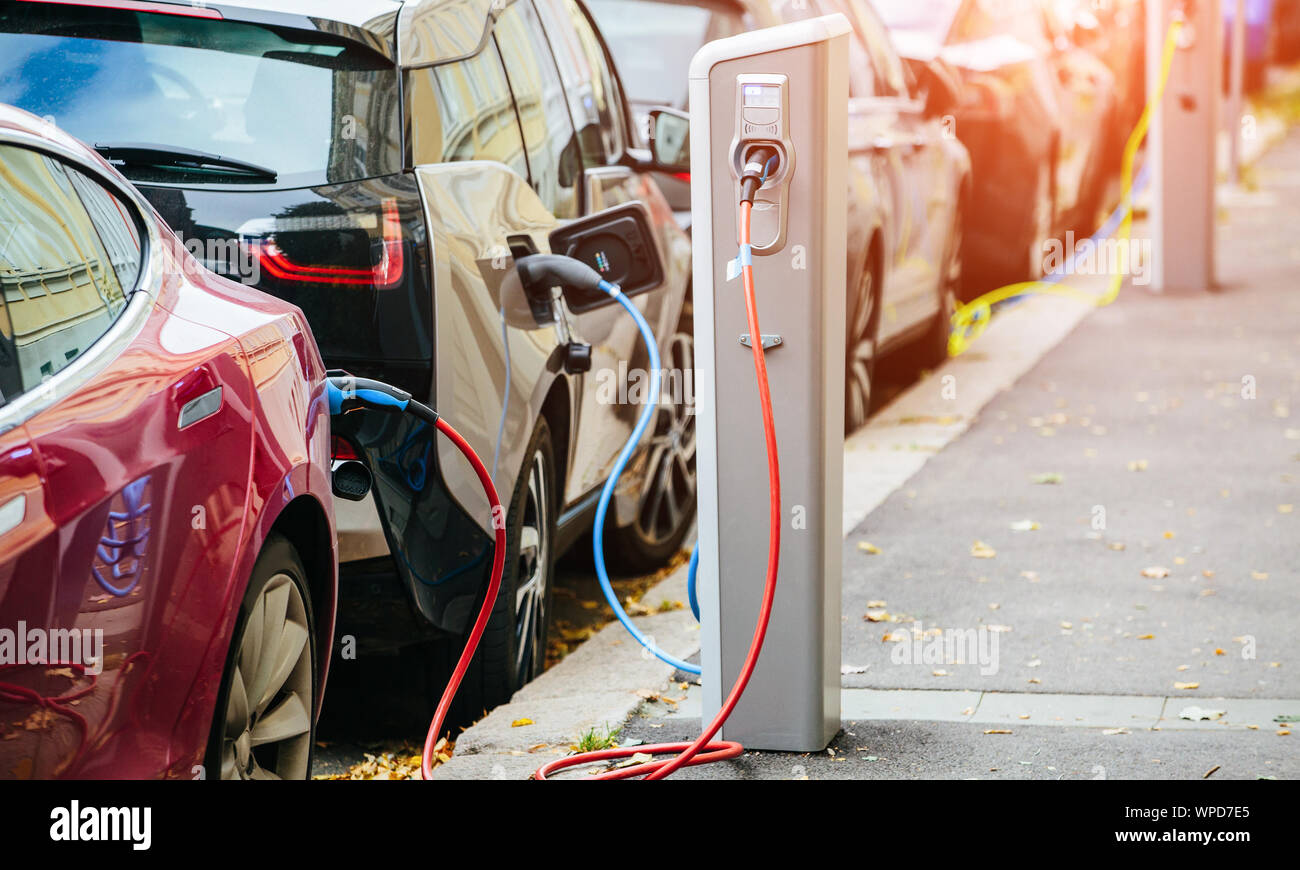 Charging modern electric cars (new energy vehicles, NEV) on the street ...