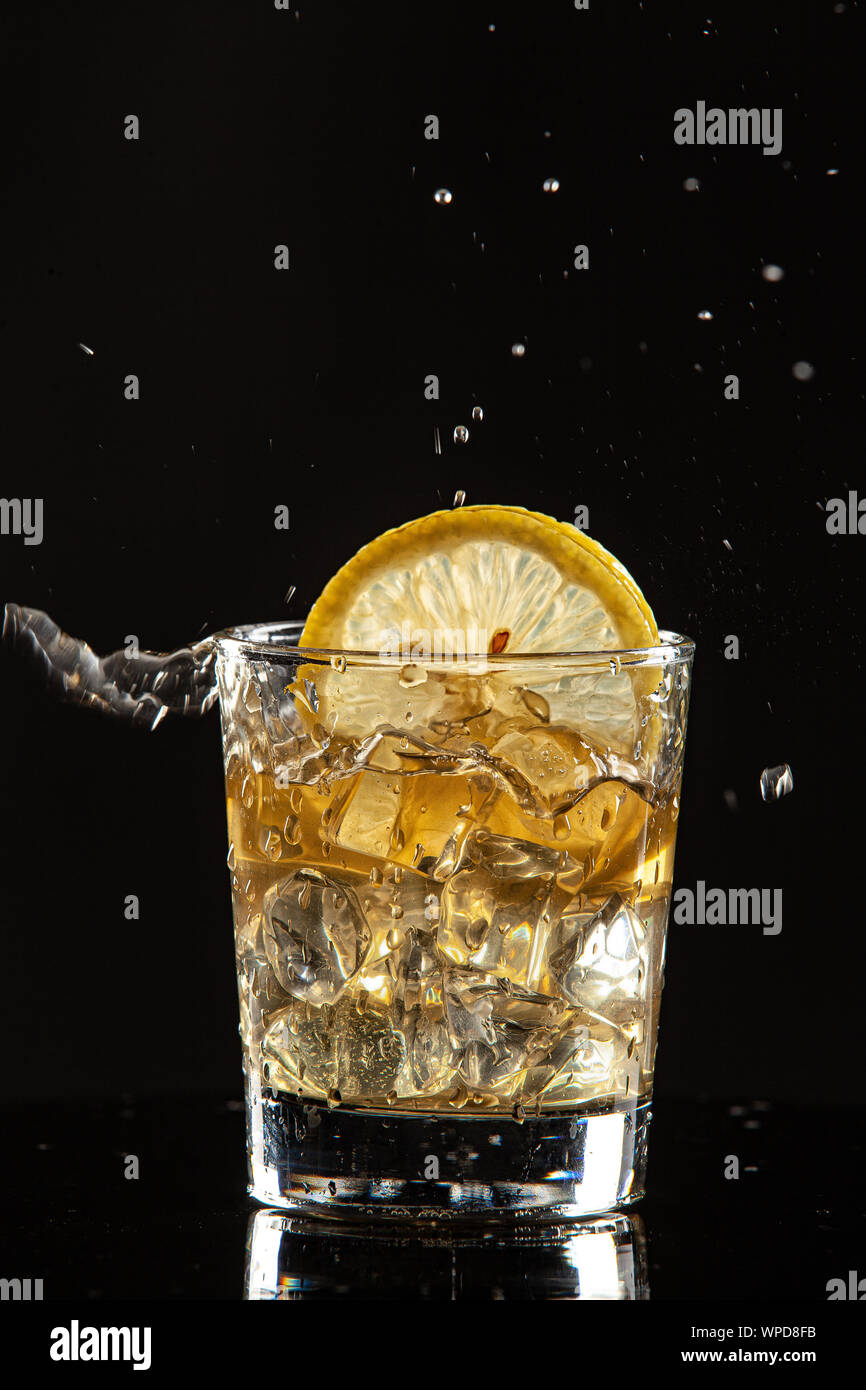 Glass of beverage, ice and lemon on a black studio background Stock ...