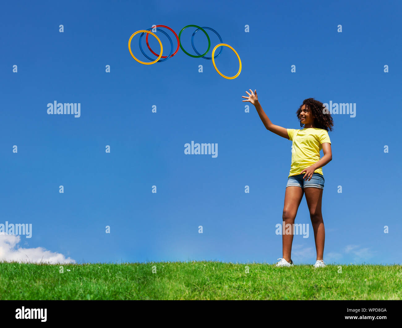 Curly hair black girl throwing hoops in the air Stock Photo - Alamy