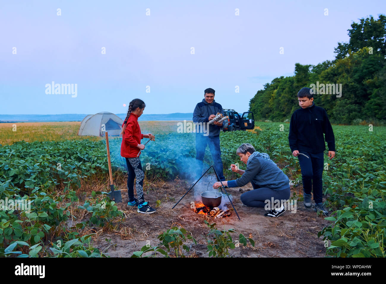 Family traveling and camping, twilight, cooking on the fire. Beautiful ...