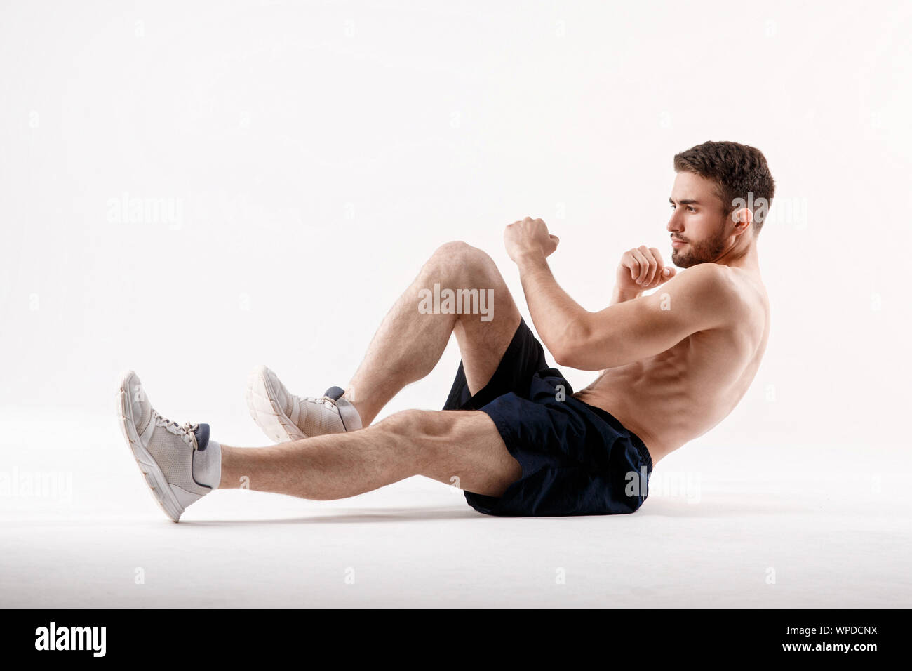 young man with a beard of a sports physique does an exercise on the ...