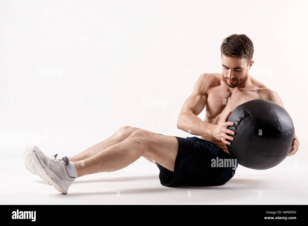 young man with a beard of a sports physique does an exercise on the ...