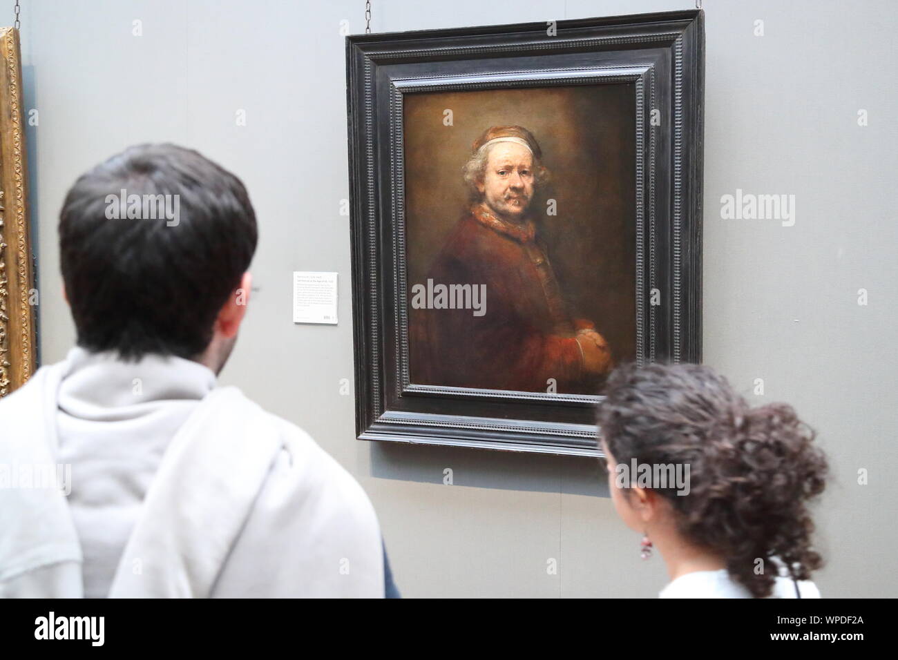 A young couple standing in front of the Self-portrait at the age of 63 ...
