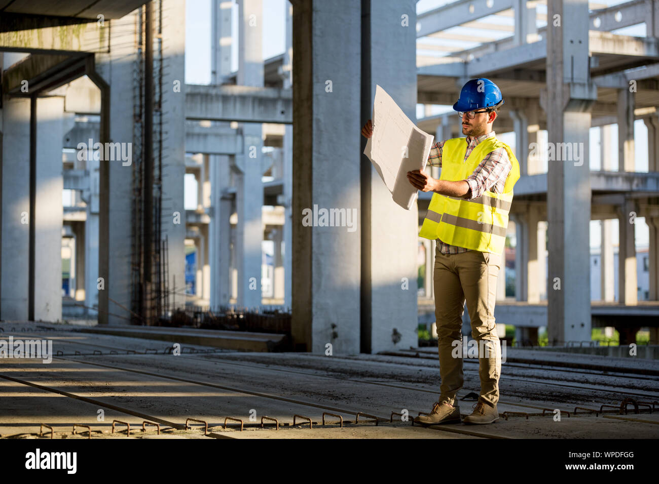 Engineer working on construction site and holding blueprint Stock Photo ...