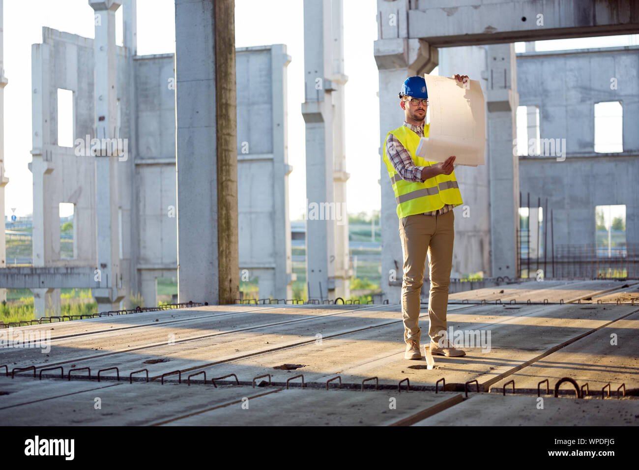 Engineer working on construction site and holding blueprint Stock Photo ...