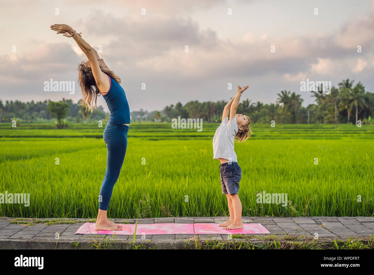 Boy and his yoga teacher doing yoga in a rice field Stock Photo - Alamy