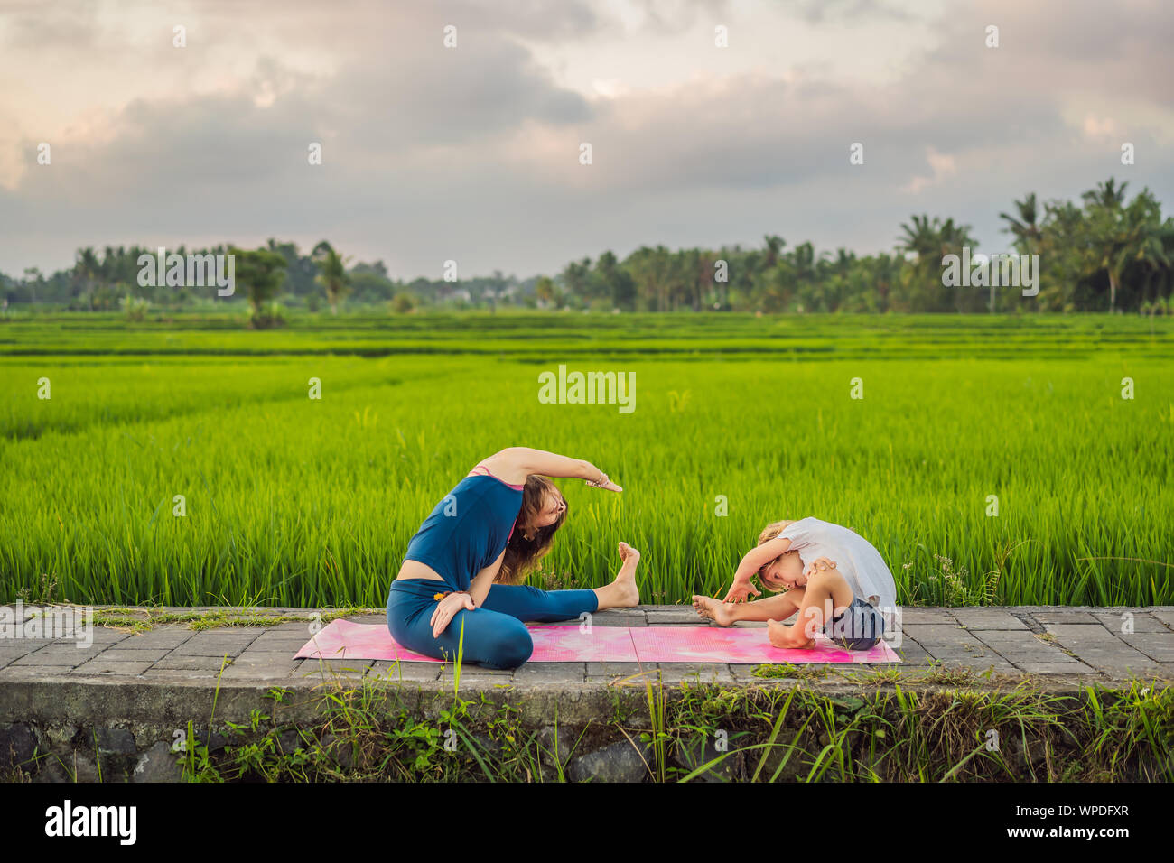 Boy and his yoga teacher doing yoga in a rice field Stock Photo - Alamy