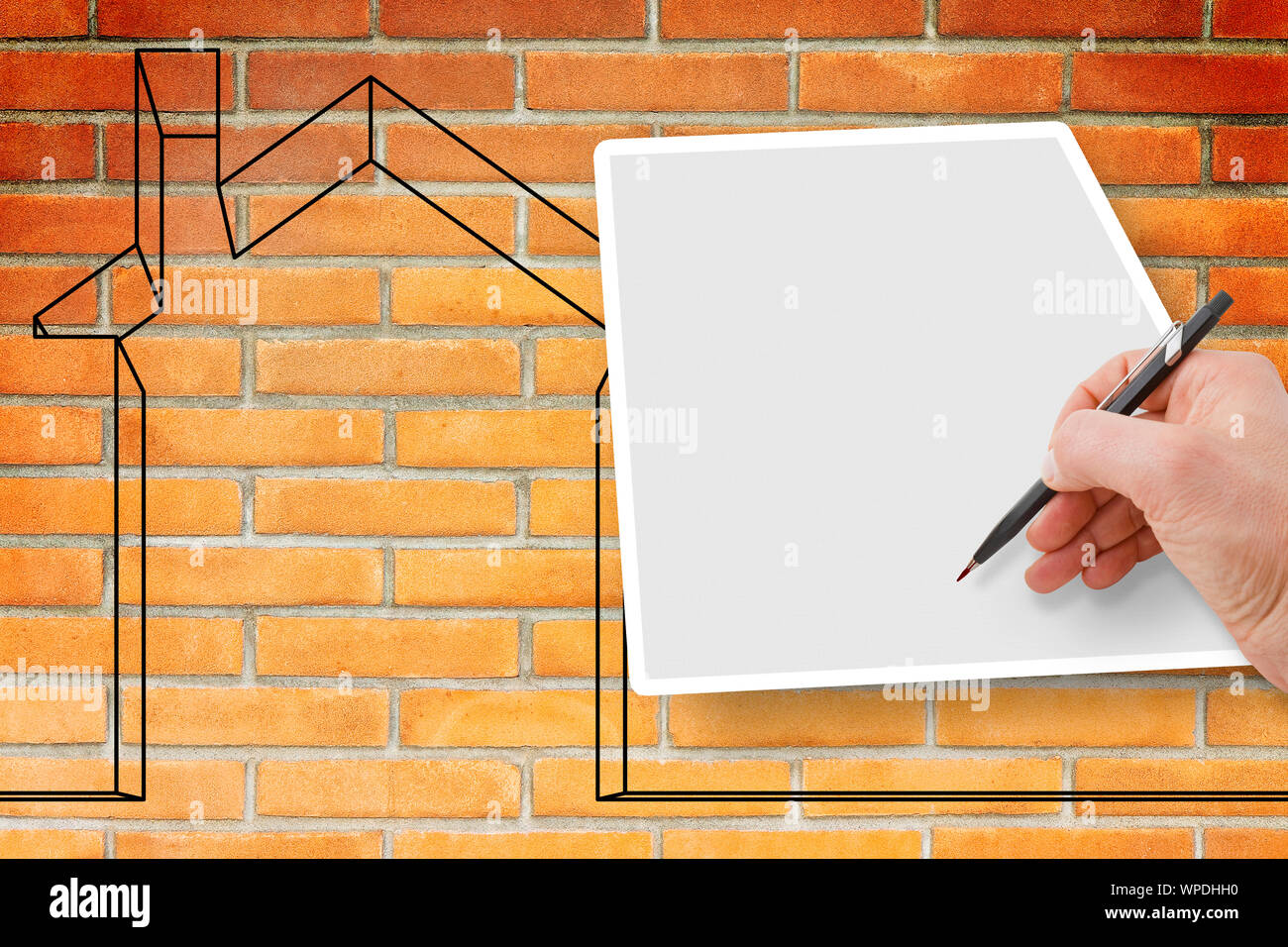 Hand writing on a blank sheet with a house outline against a brick wall ...