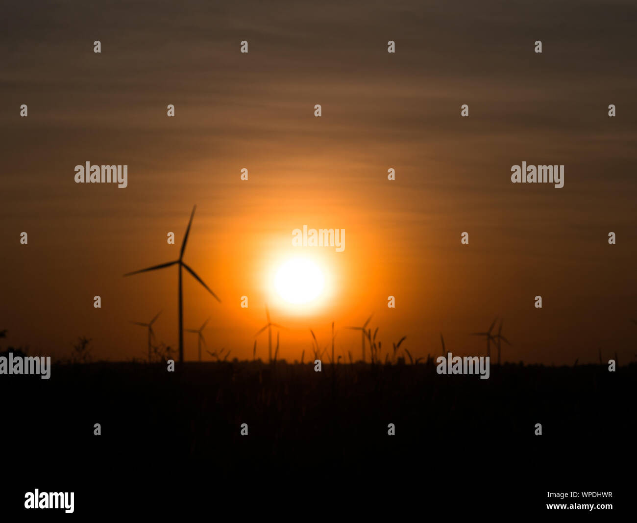 Silhouette wind turbine and grass field with sunset background with ...