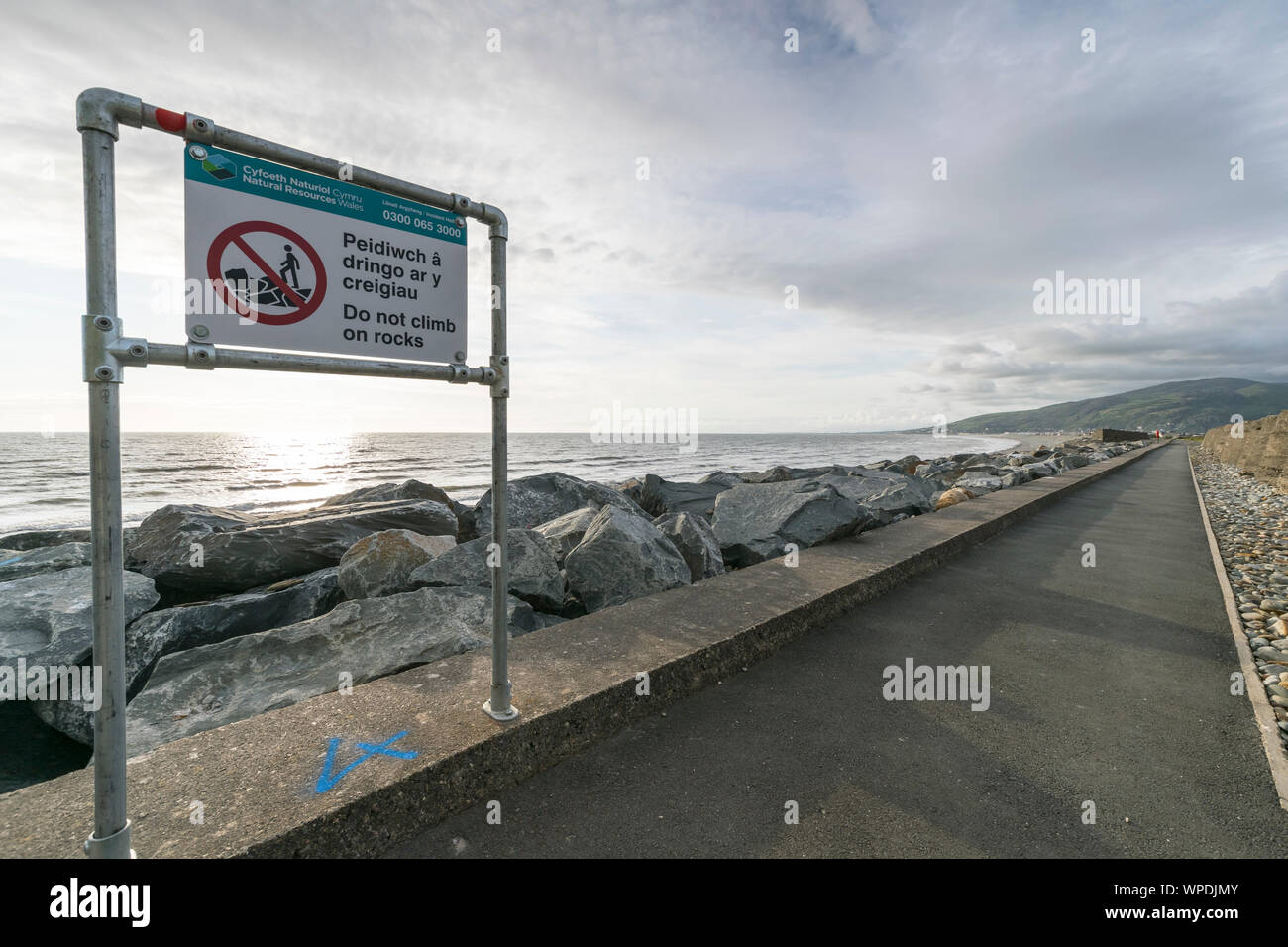 Do not climb on the rocks warning sign on Fairbourne beach Gwynedd in ...