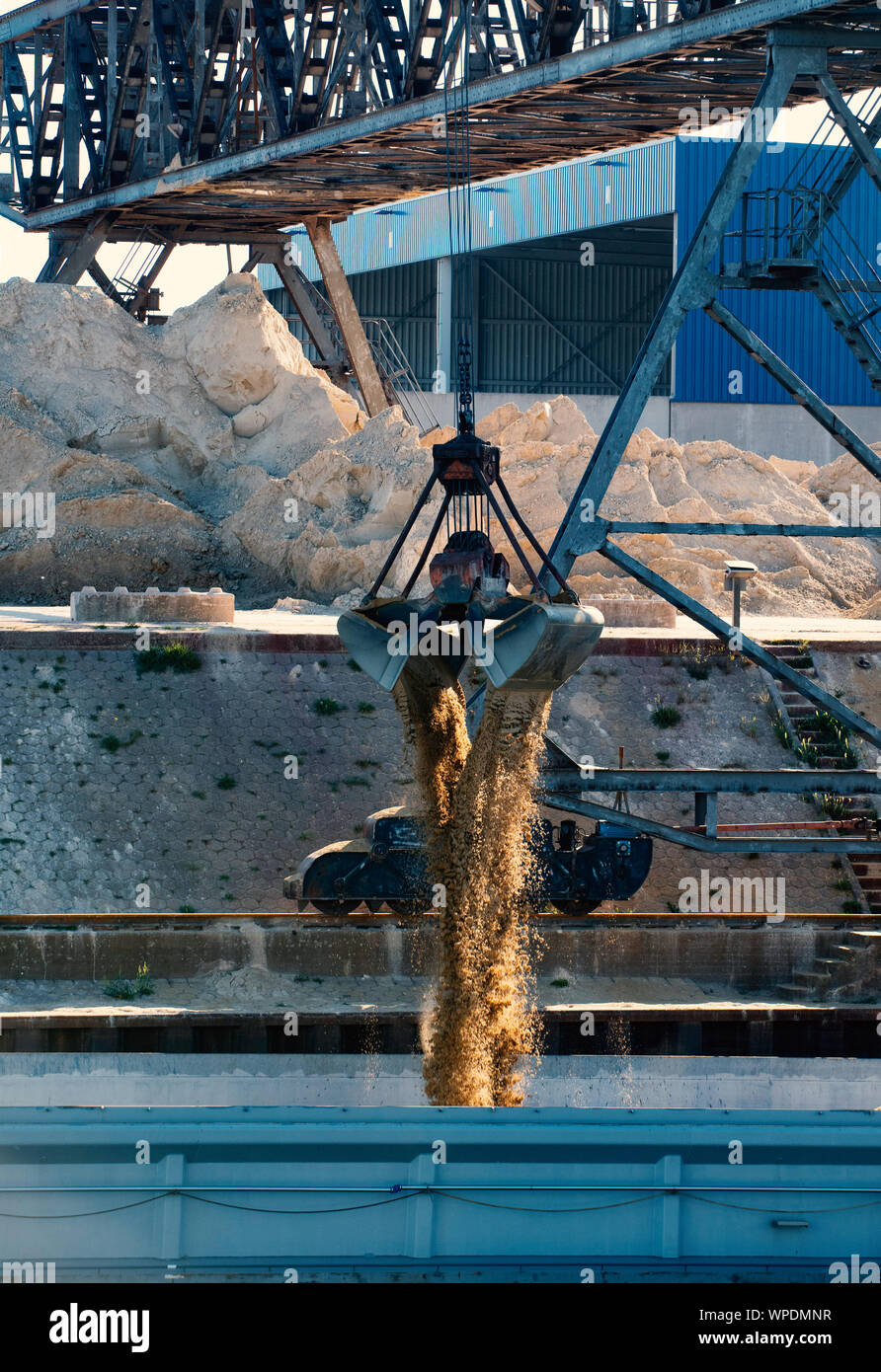 Industrial scene of crane loading sand in vessel Stock Photo - Alamy