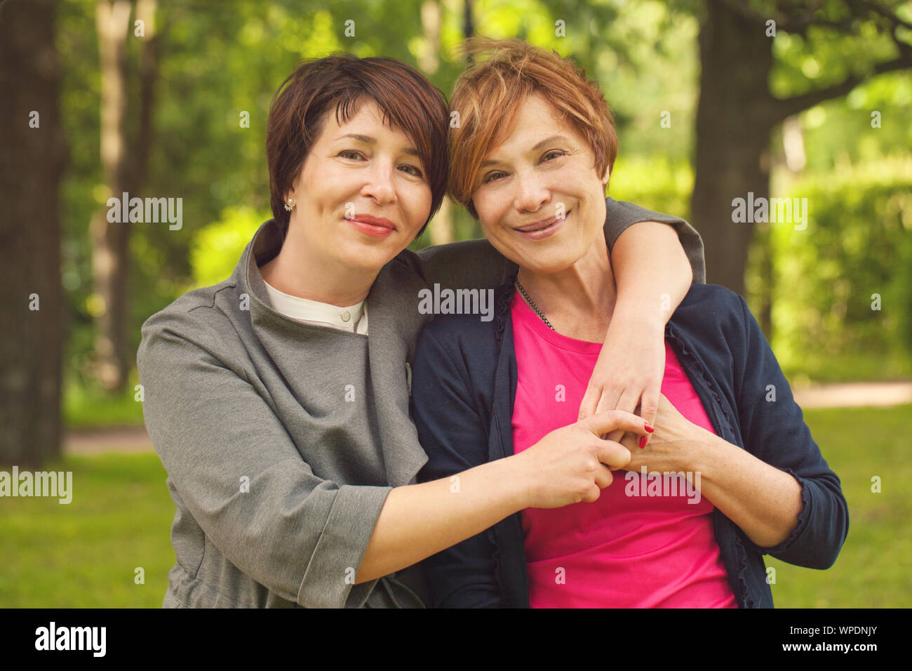 Two happy women walking in summer park, portrait Stock Photo - Alamy
