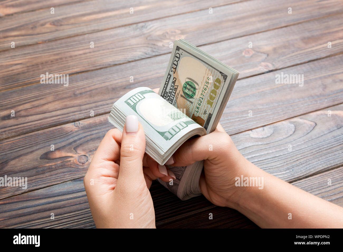 Perspective view of female hands counting money. One hundred dollar ...