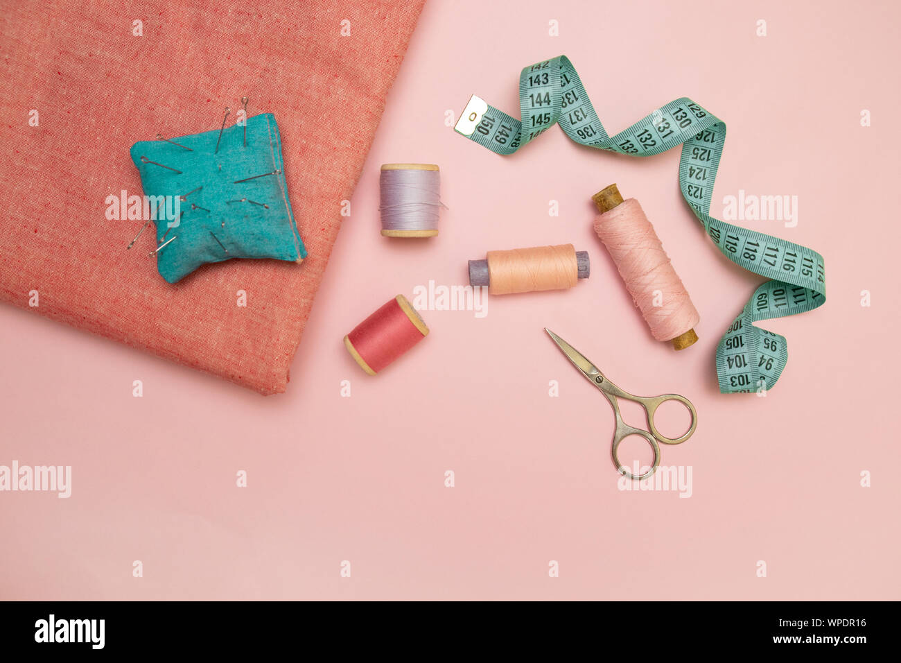 Sewing accessories and fabric on a pink background. Tailoring and craft ...