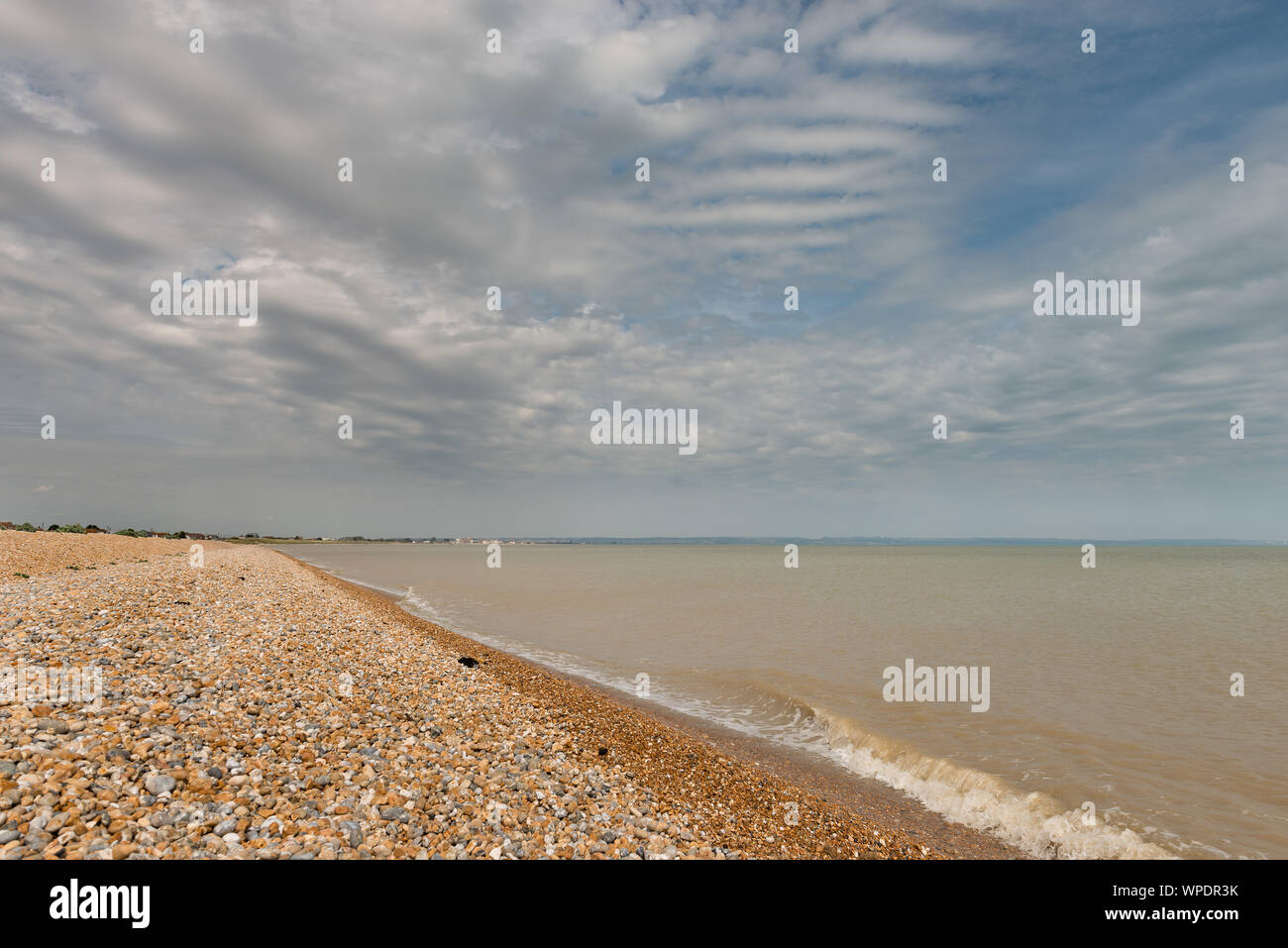Bleak shingle shoreline with English Channel at high tide, with ...
