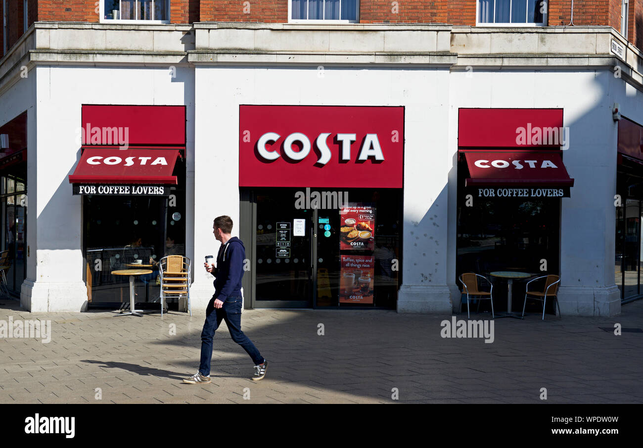 Young man walking past a branch of Costa Coffee, Hull, East Yorkshire ...