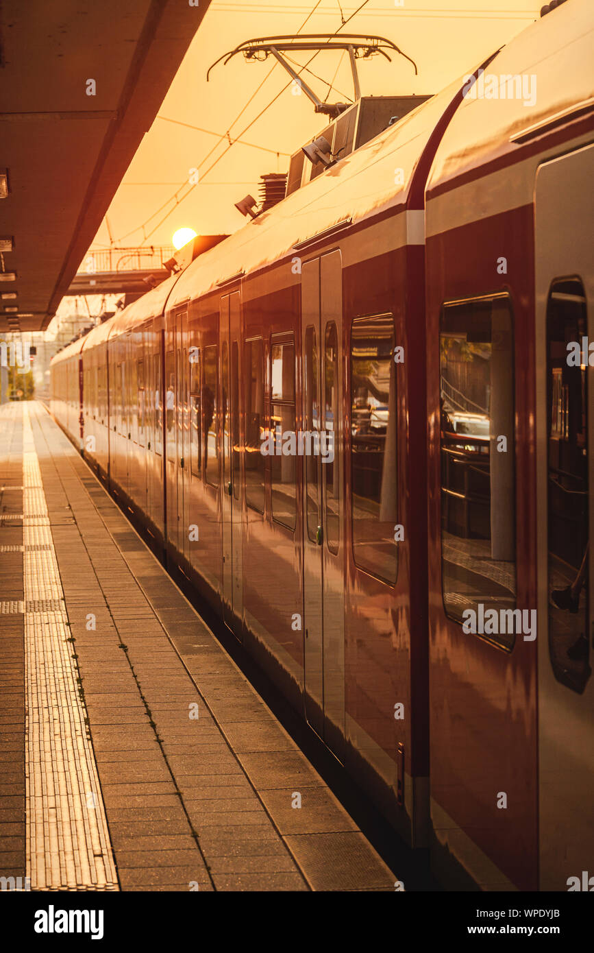 Red train on the platform at sunrise, german public transportation ...