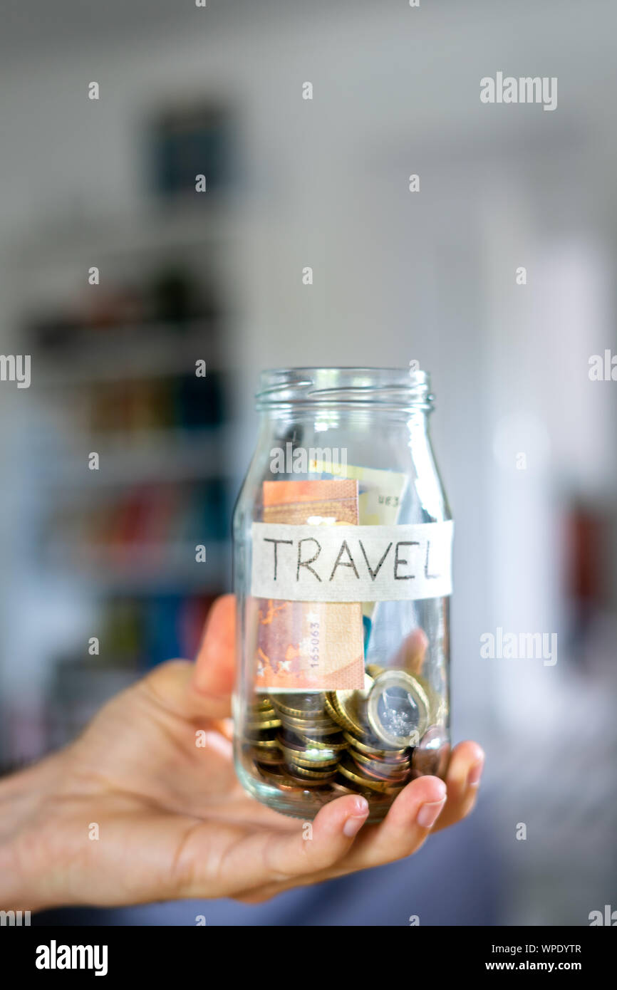 Man's hand holding a jar with euro coins and notes and a handwritten ...
