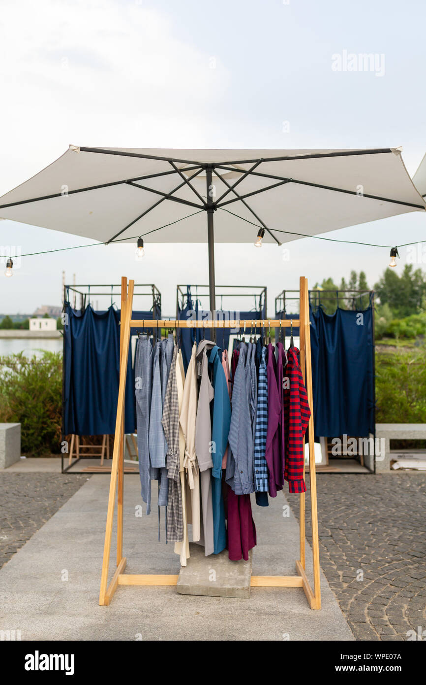 Racks with clothes outdoors. Designer sells clothes at a city fair ...