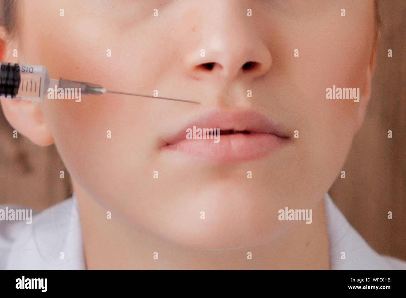 Doctor in gloves giving woman botox injections in lips, on pink ...