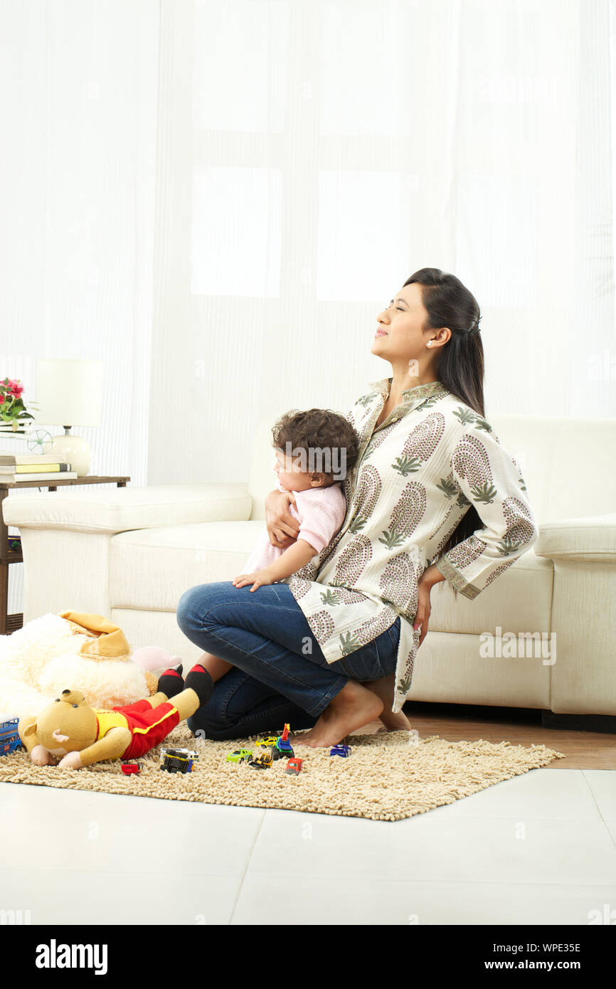 Mother carrying baby and suffering from lower back pain Stock Photo - Alamy
