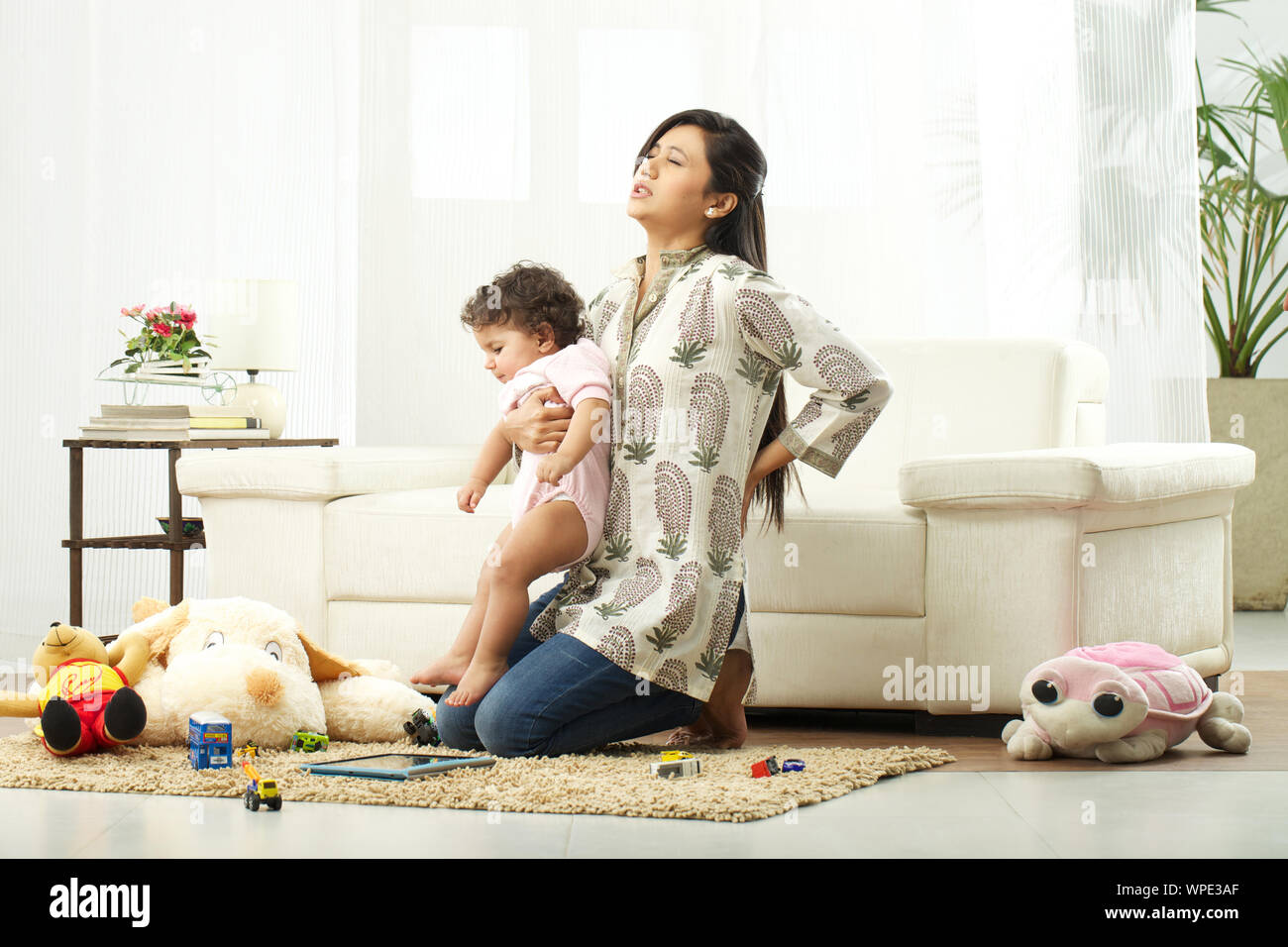 Mother carrying baby and suffering from lower back pain Stock Photo - Alamy