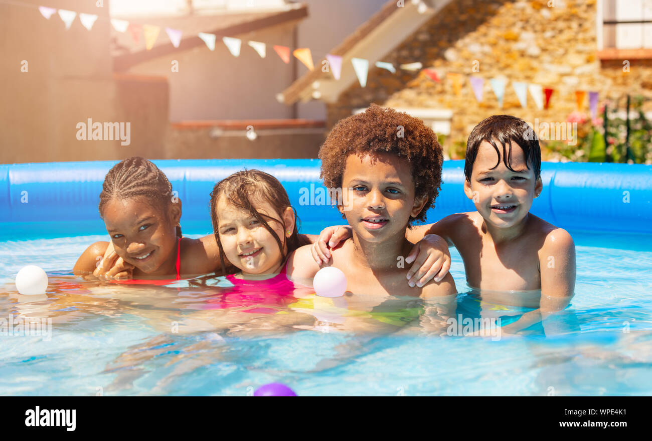 Four kids play in backyard swimming pool together Stock Photo - Alamy