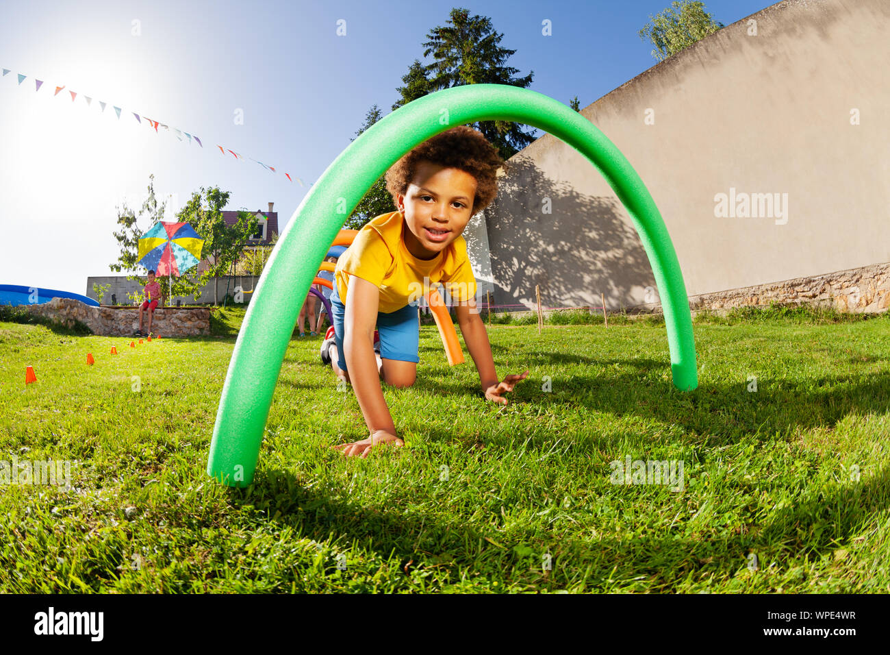 Kids crawl under course of barriers on his fours Stock Photo - Alamy