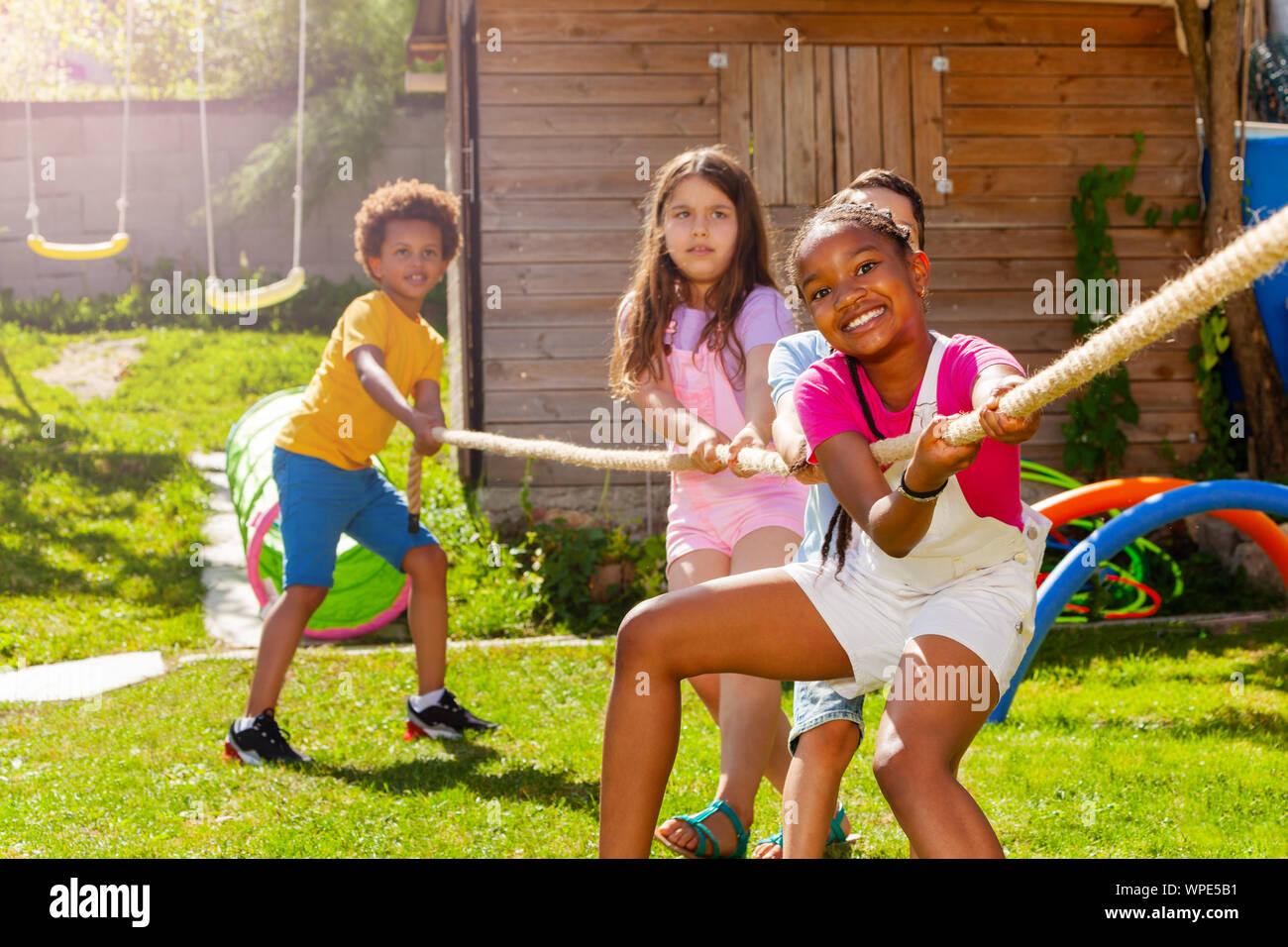 Group of diverse children pull rope in competition Stock Photo - Alamy