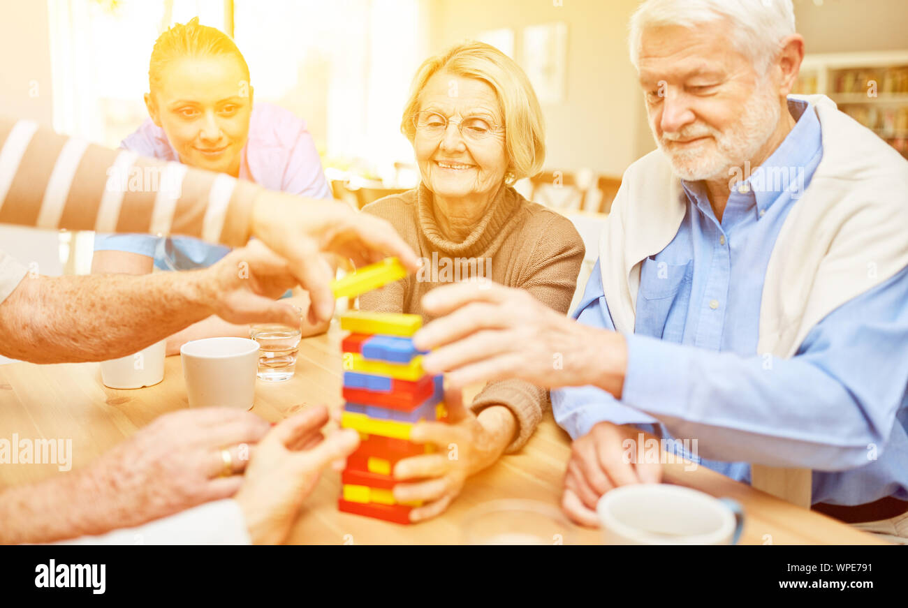 Friendly seniors play together with colorful building blocks in the ...