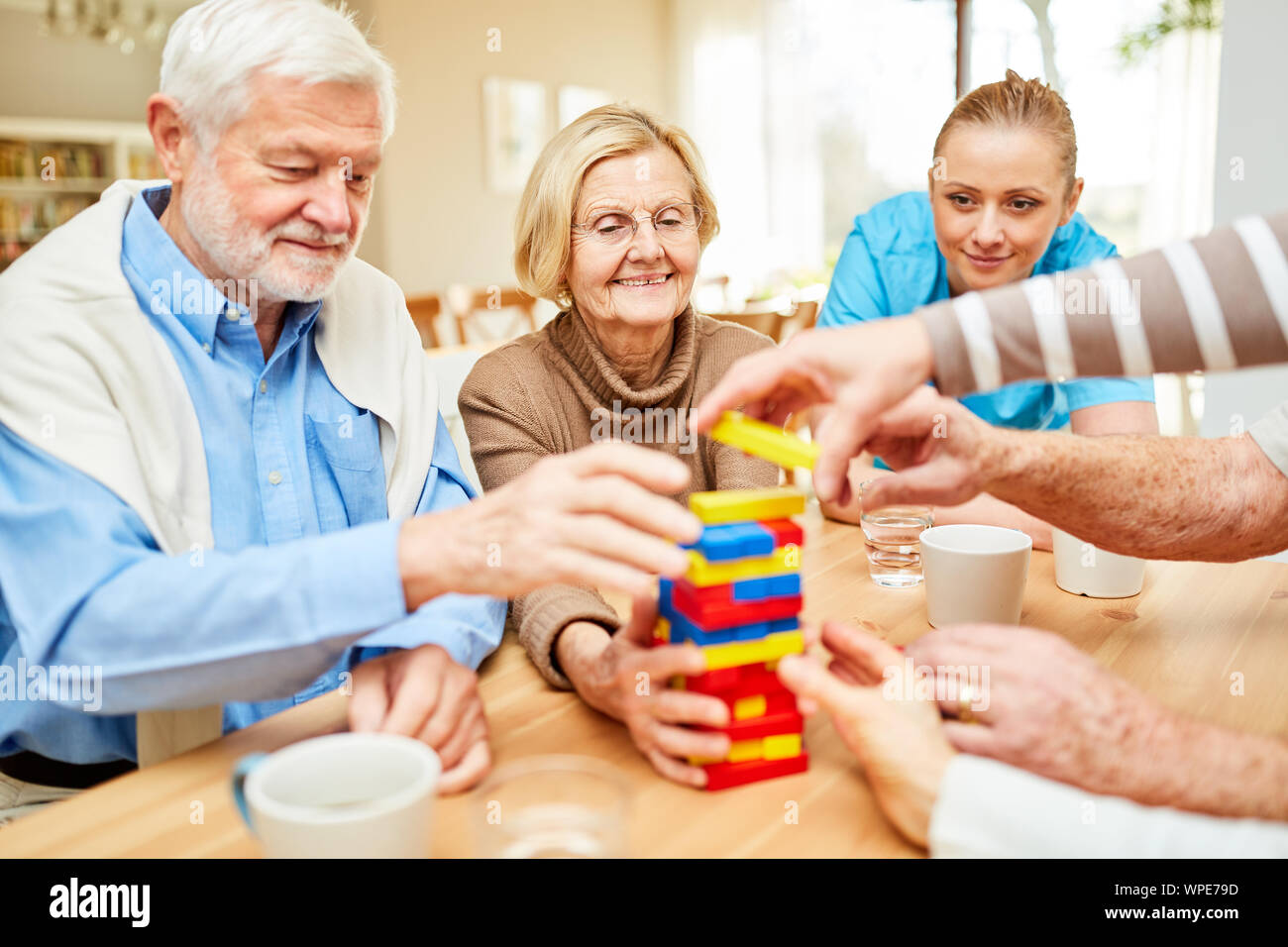 Group of seniors plays together with colorful building blocks in ...