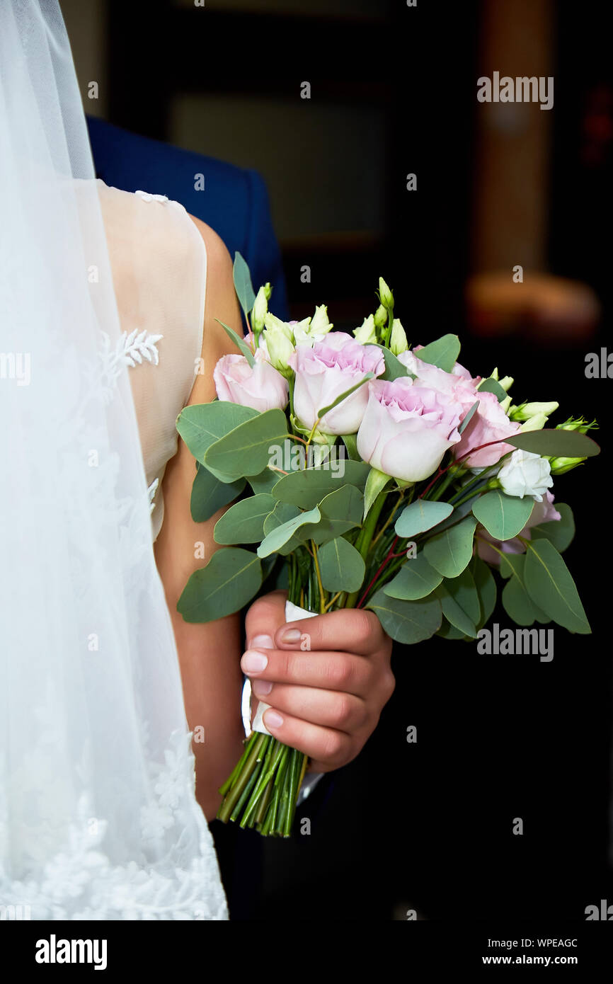 Bride in wedding dress and groom with a bouquet of flowers and greens ...