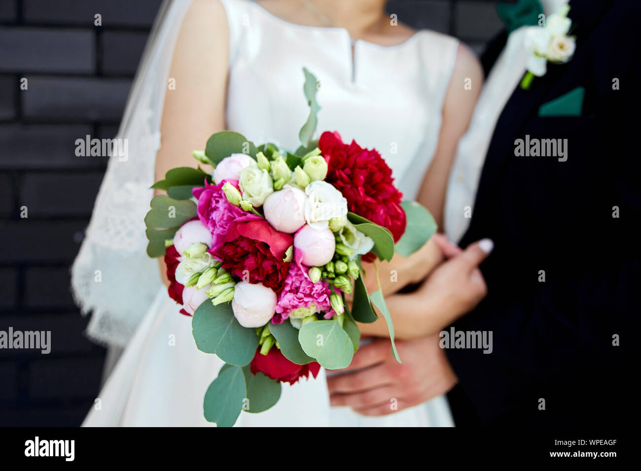 Bride in wedding dress and groom with a bouquet of flowers and greens ...