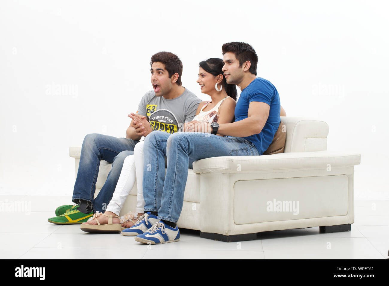 Group of friend watching TV and smiling Stock Photo - Alamy