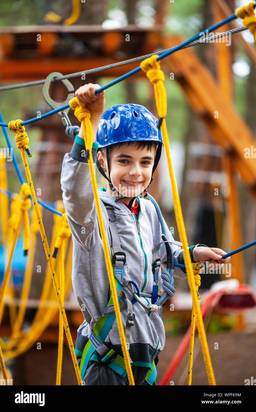 Young boy climbing pass obstacles in rope. Child in forest adventure ...