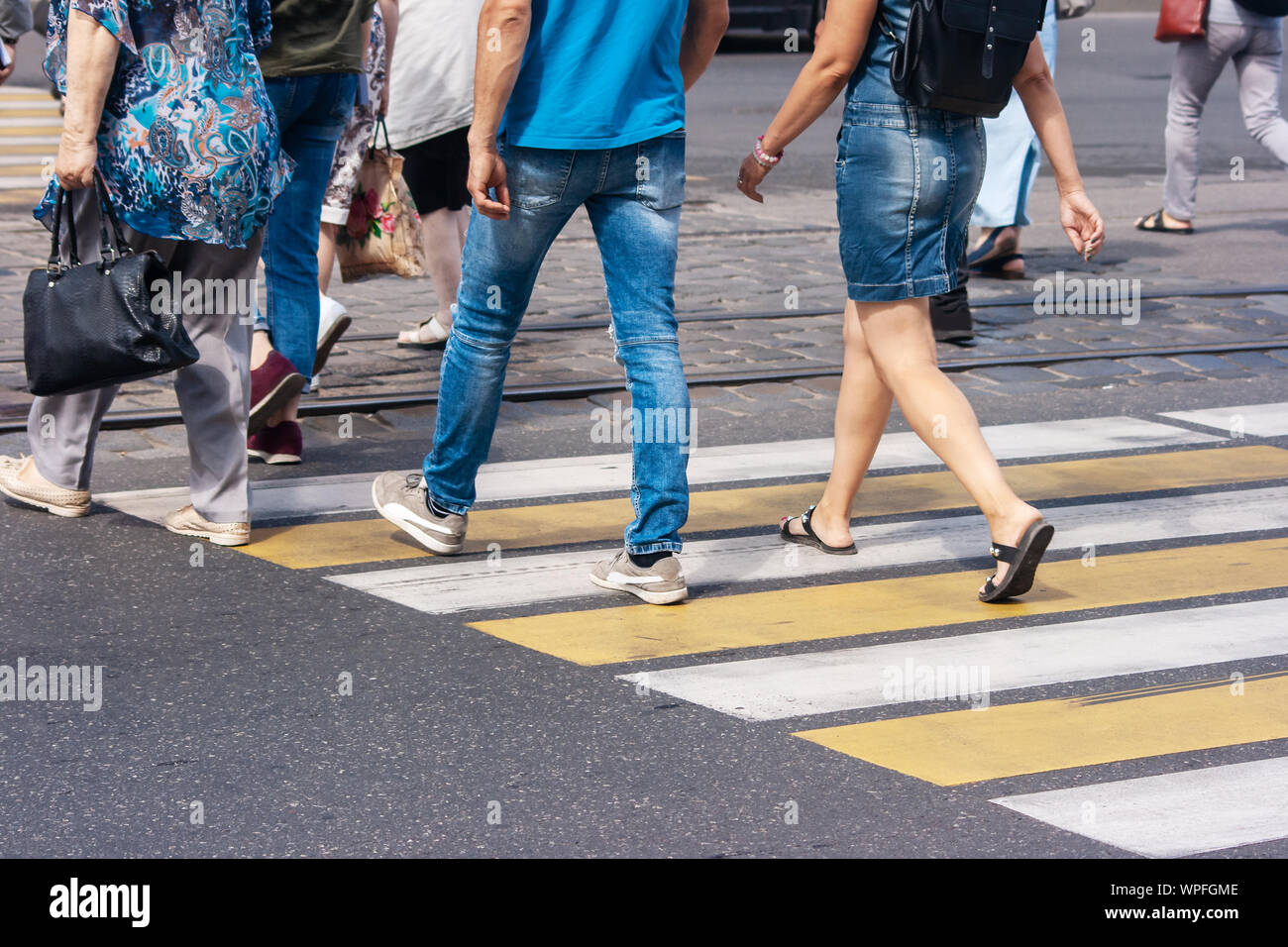 pedestrians crossing the road at a crosswalk in the city on summer day ...